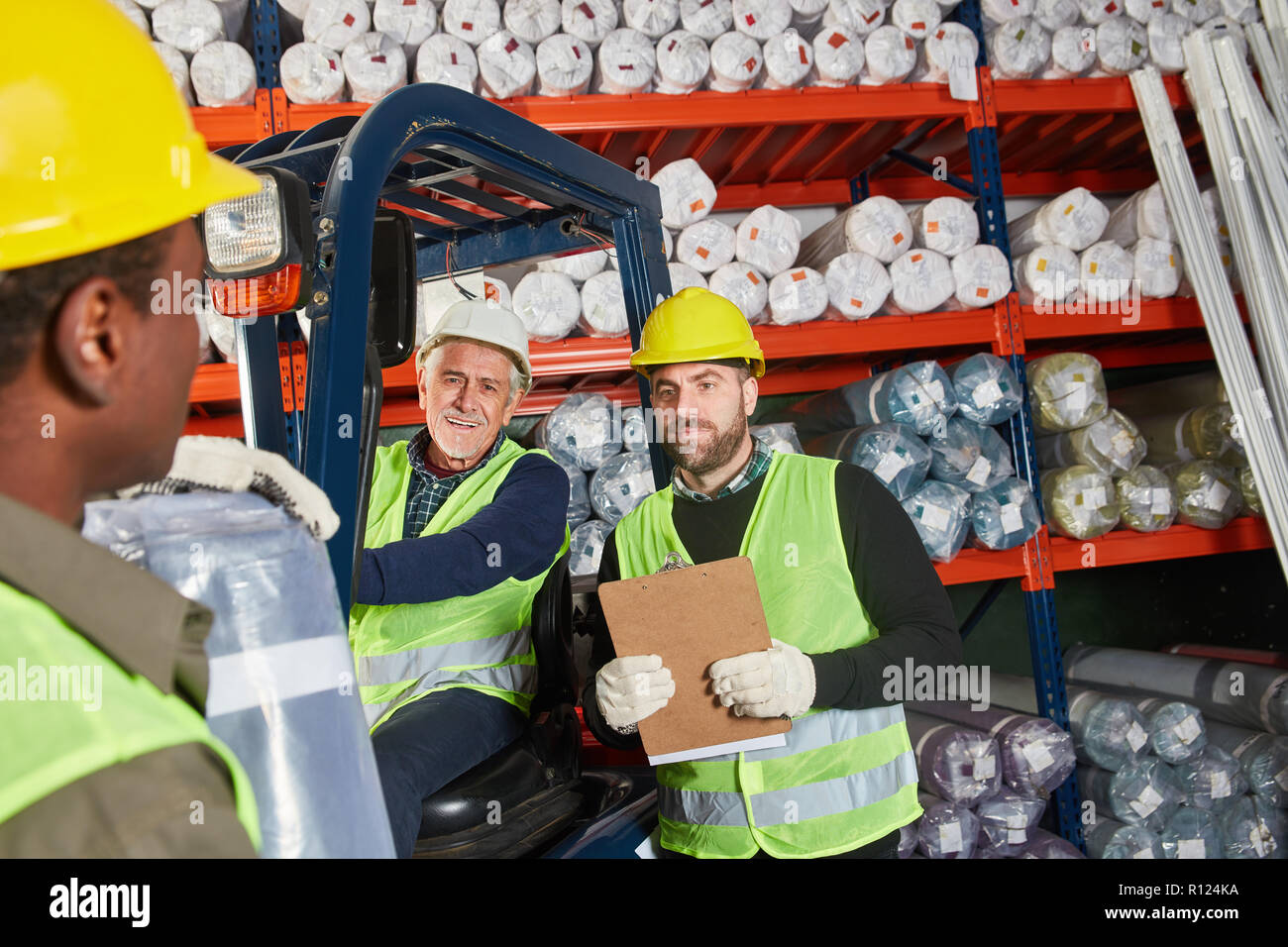 Workers as a logistics team in the carpet warehouse work together in ...