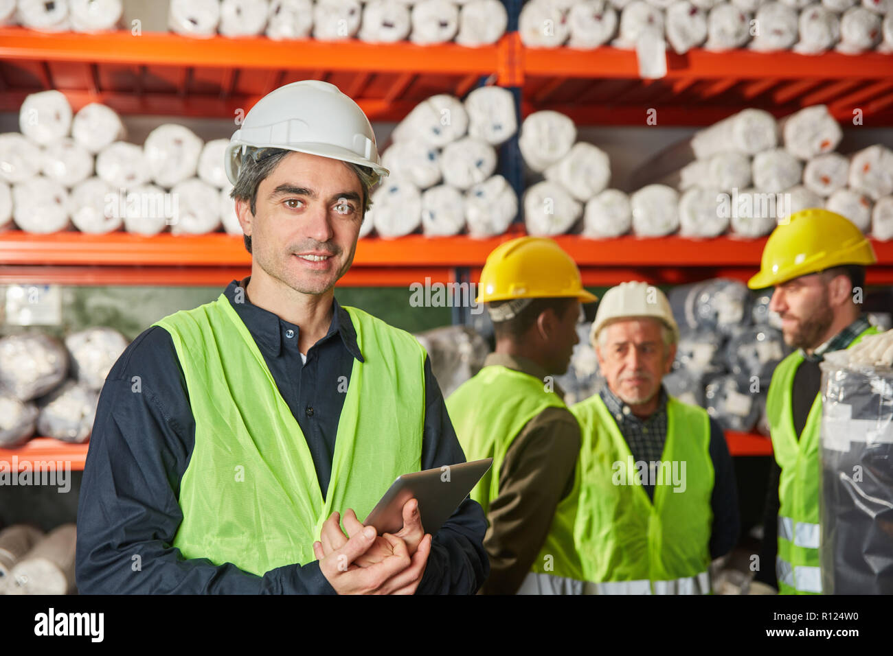 Warehouse worker as a picker with colleagues in warehouse in wholesale ...