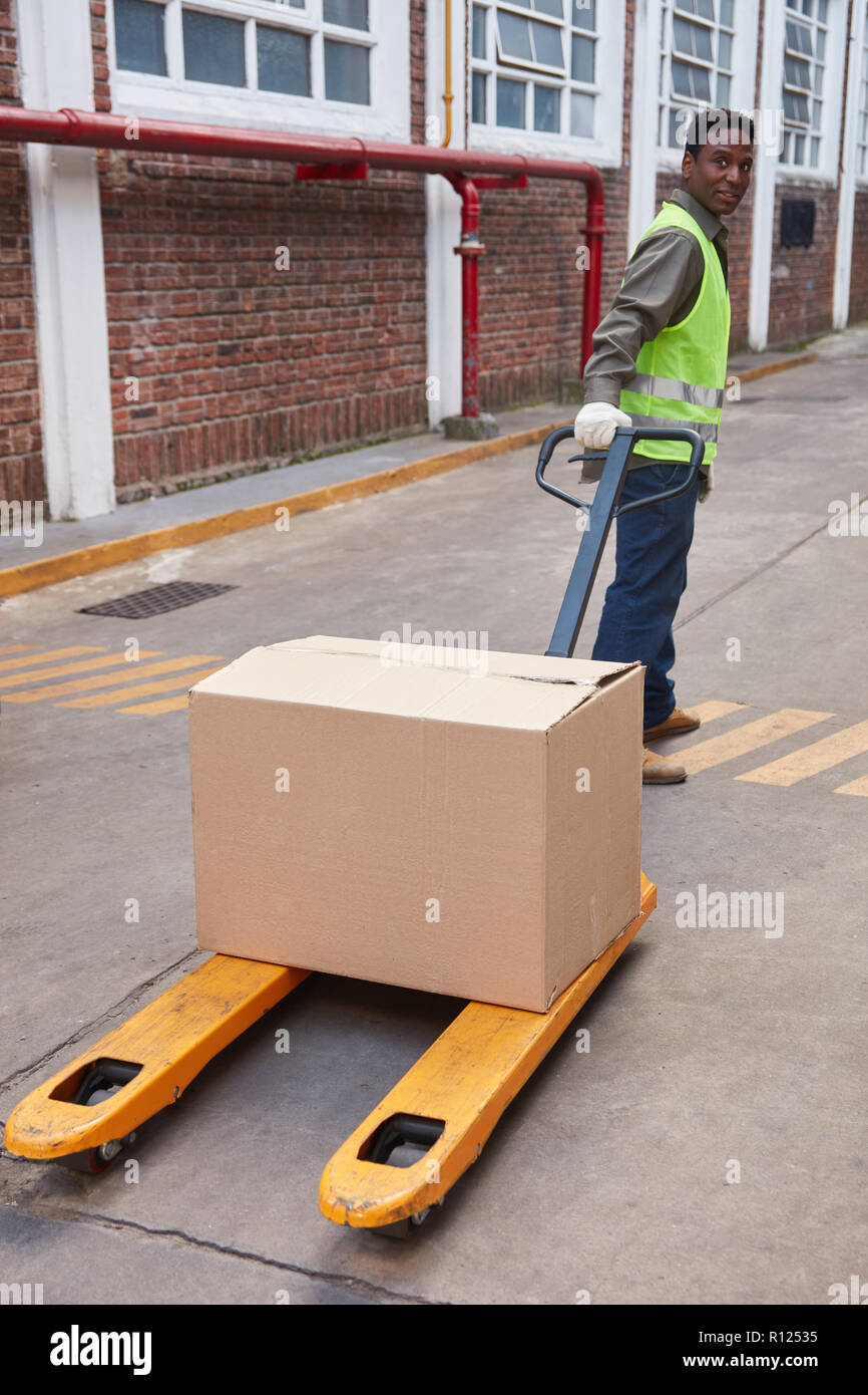 Warehouse worker in front of the warehouse with pallet truck transports ...