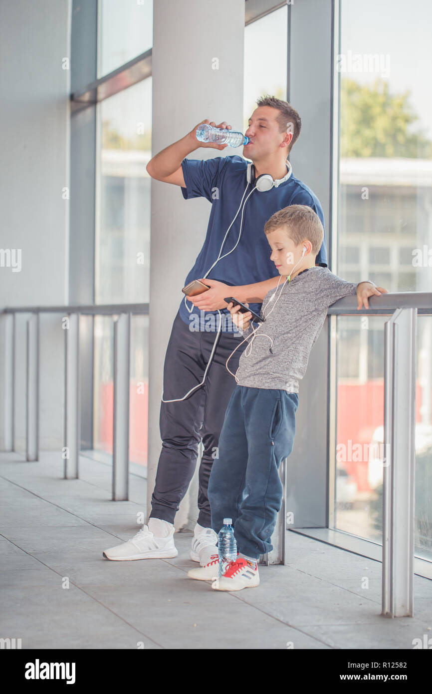 Little boy and his father taking a break, drinking water and listening ...