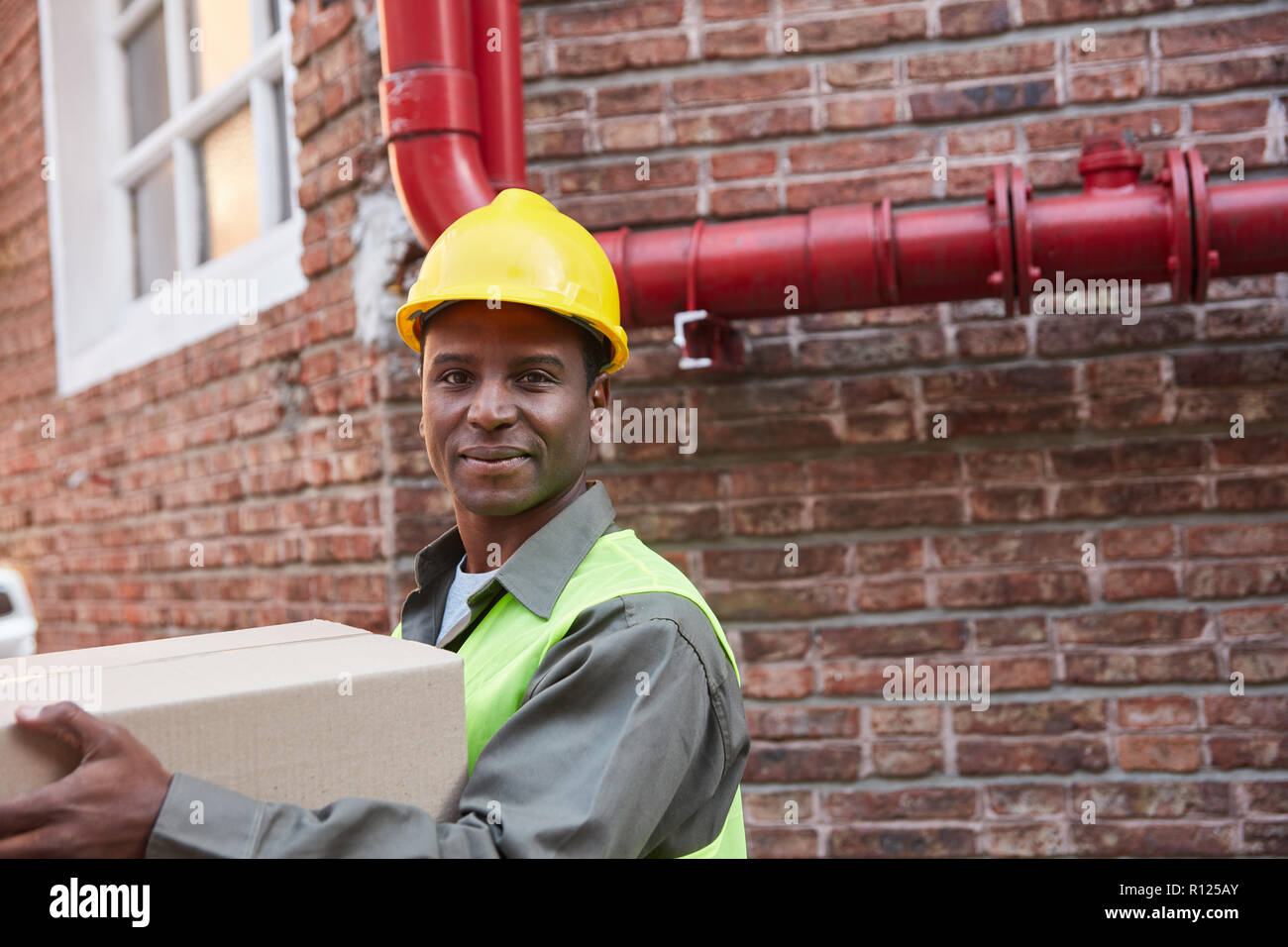 African logistics worker in front of the shipping center carries a ...