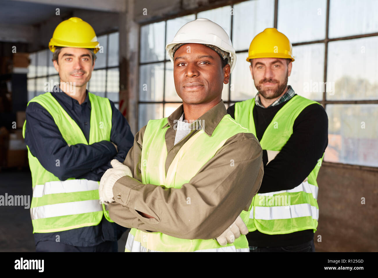 Three warehouse workers as a proud international logistics team in a ...