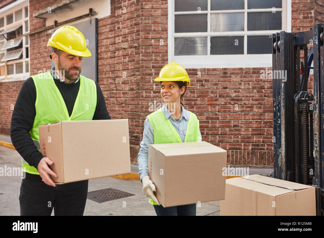Two logistics workers carry packages together as a delivery service in ...