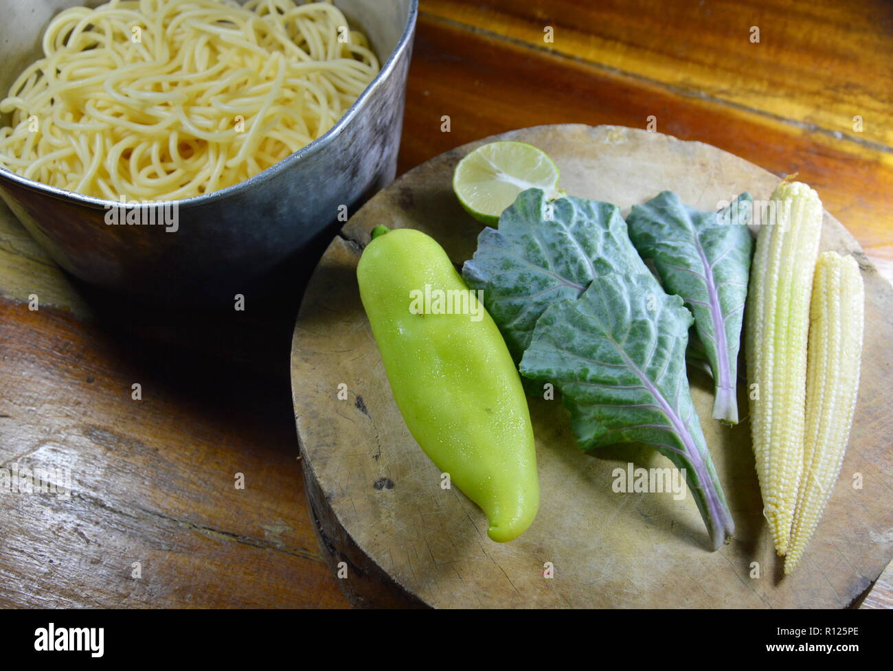 spaghetti in iron pot and vegetable on circle wooden chop block Stock ...