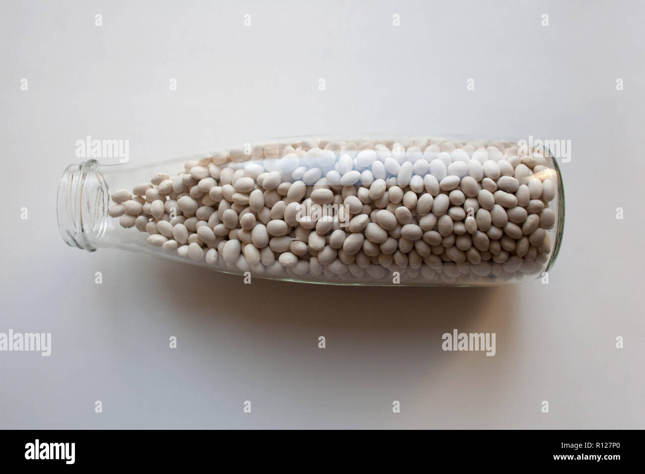 Navy beans in transparent glass bottle isolated on white background ...