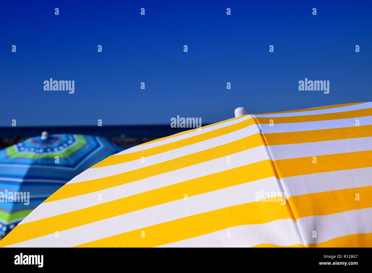 different colorful striped umbrellas on beach, yellow and white striped ...