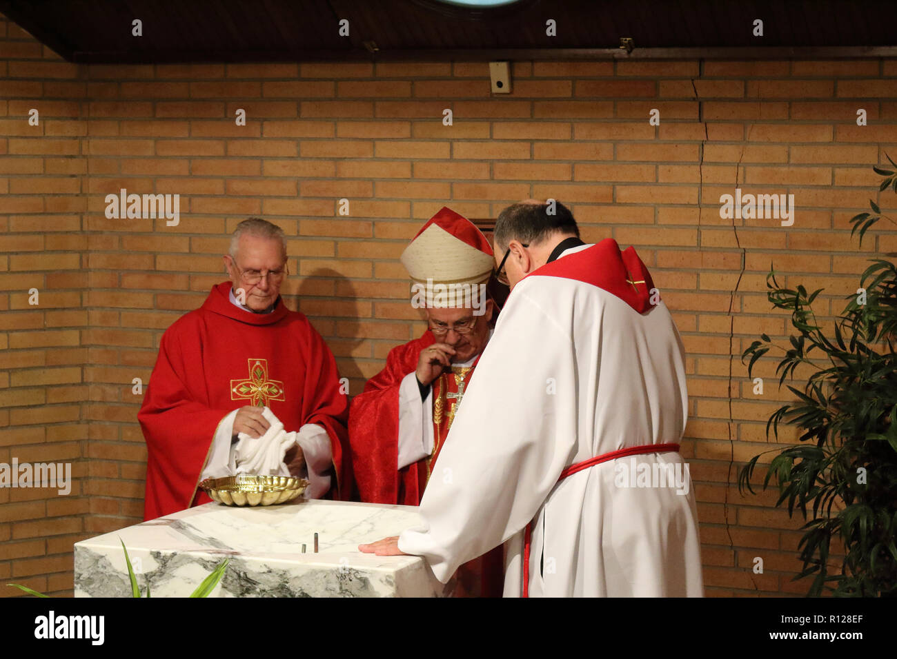 A Roman Catholic archbishop and a two priests with red vestments next ...