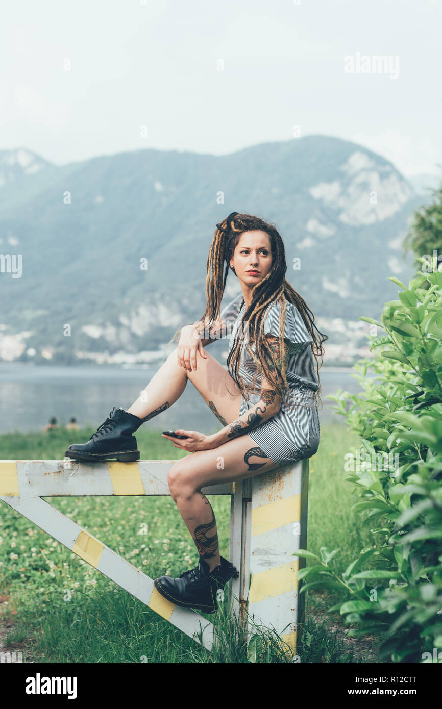 Woman sitting on wooden gate Stock Photo - Alamy