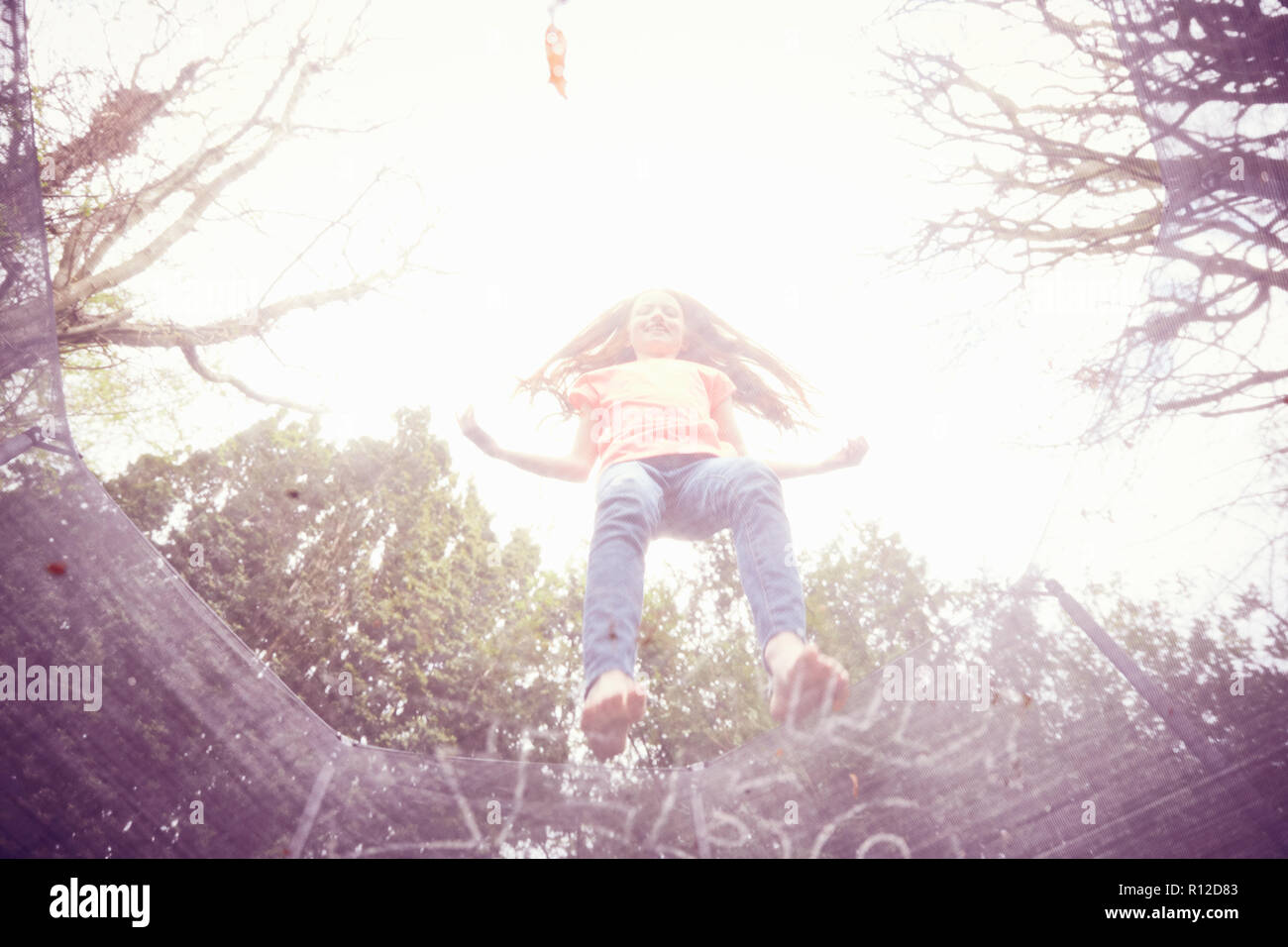 Girl jumping on trampoline, low angle view Stock Photo - Alamy