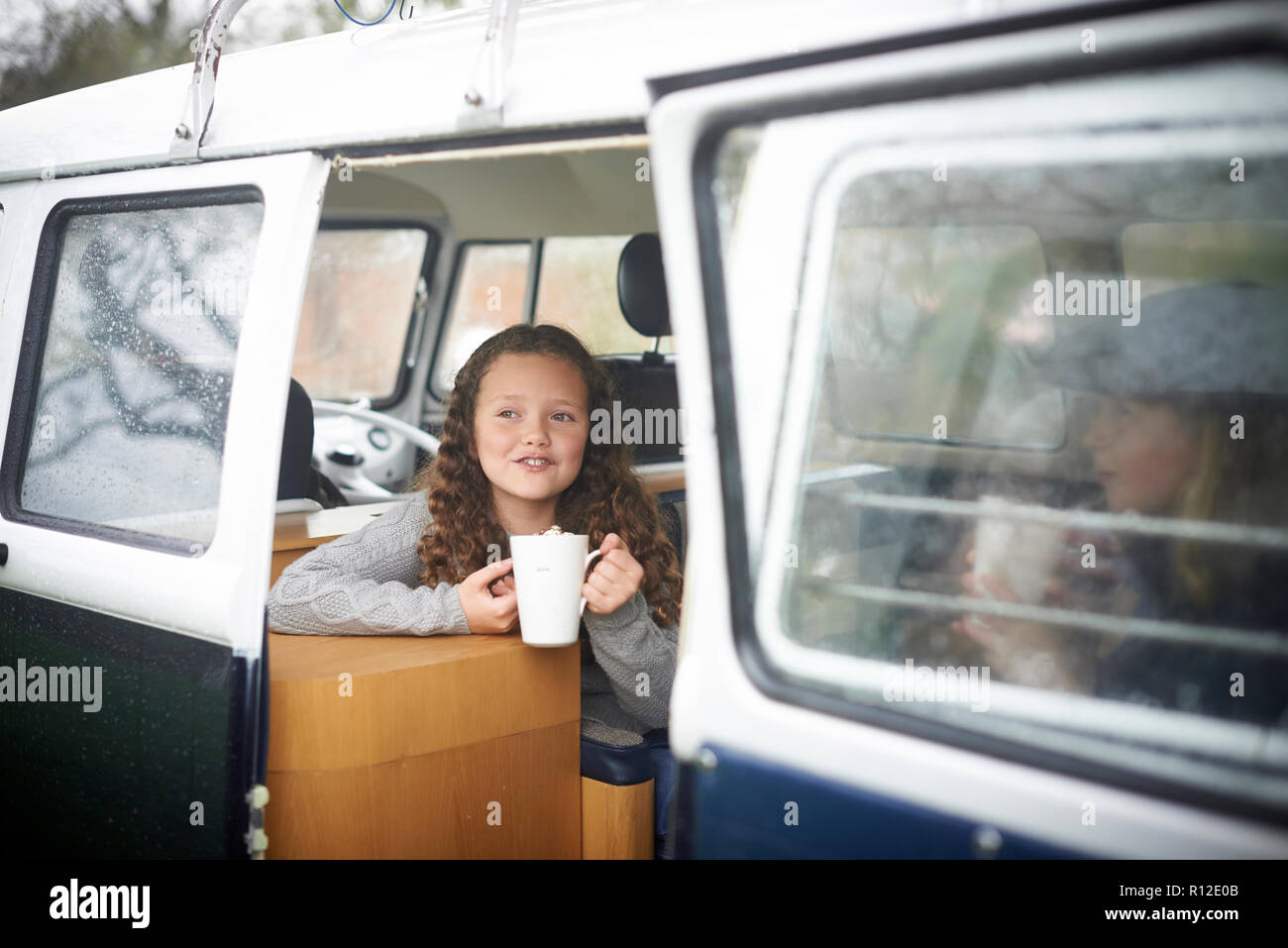 Girls with hot chocolate talking inside camper van Stock Photo - Alamy