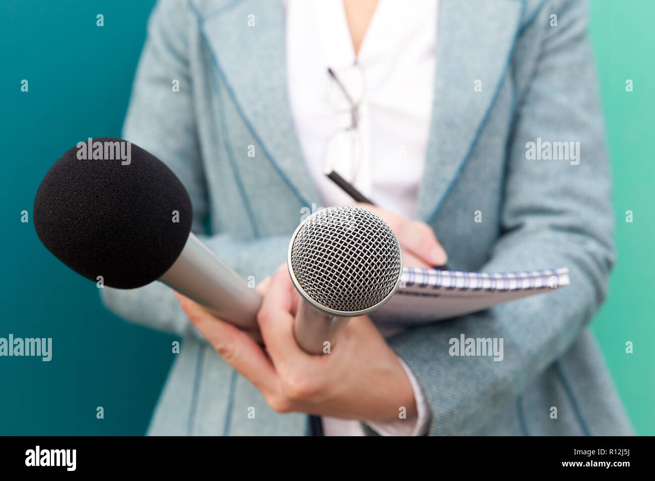 Female journalist at a press conference, taking notes, holding ...