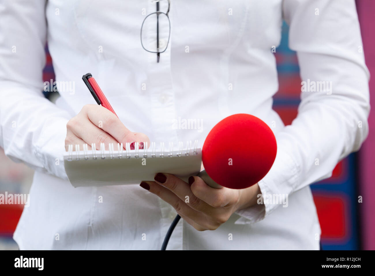 Female journalist at a press conference, taking notes, holding ...
