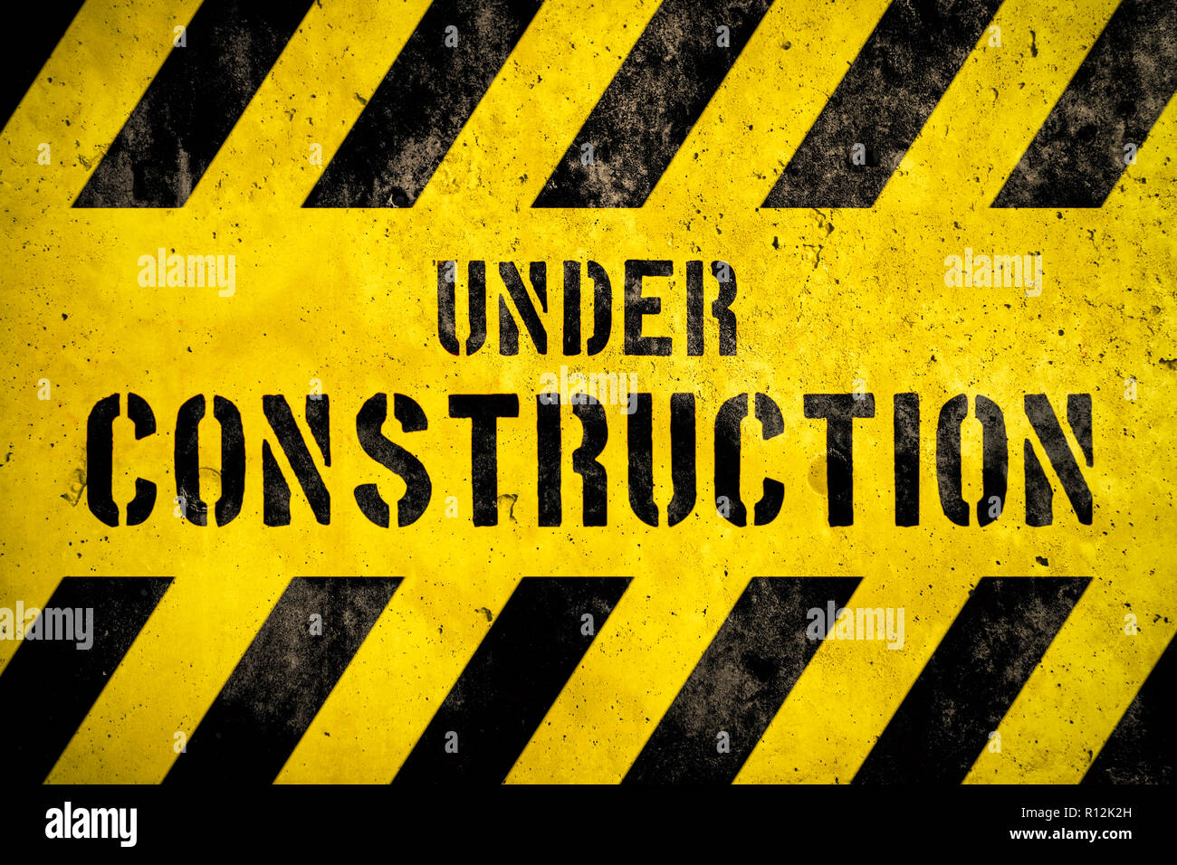 Under construction warning sign text with yellow black stripes painted ...