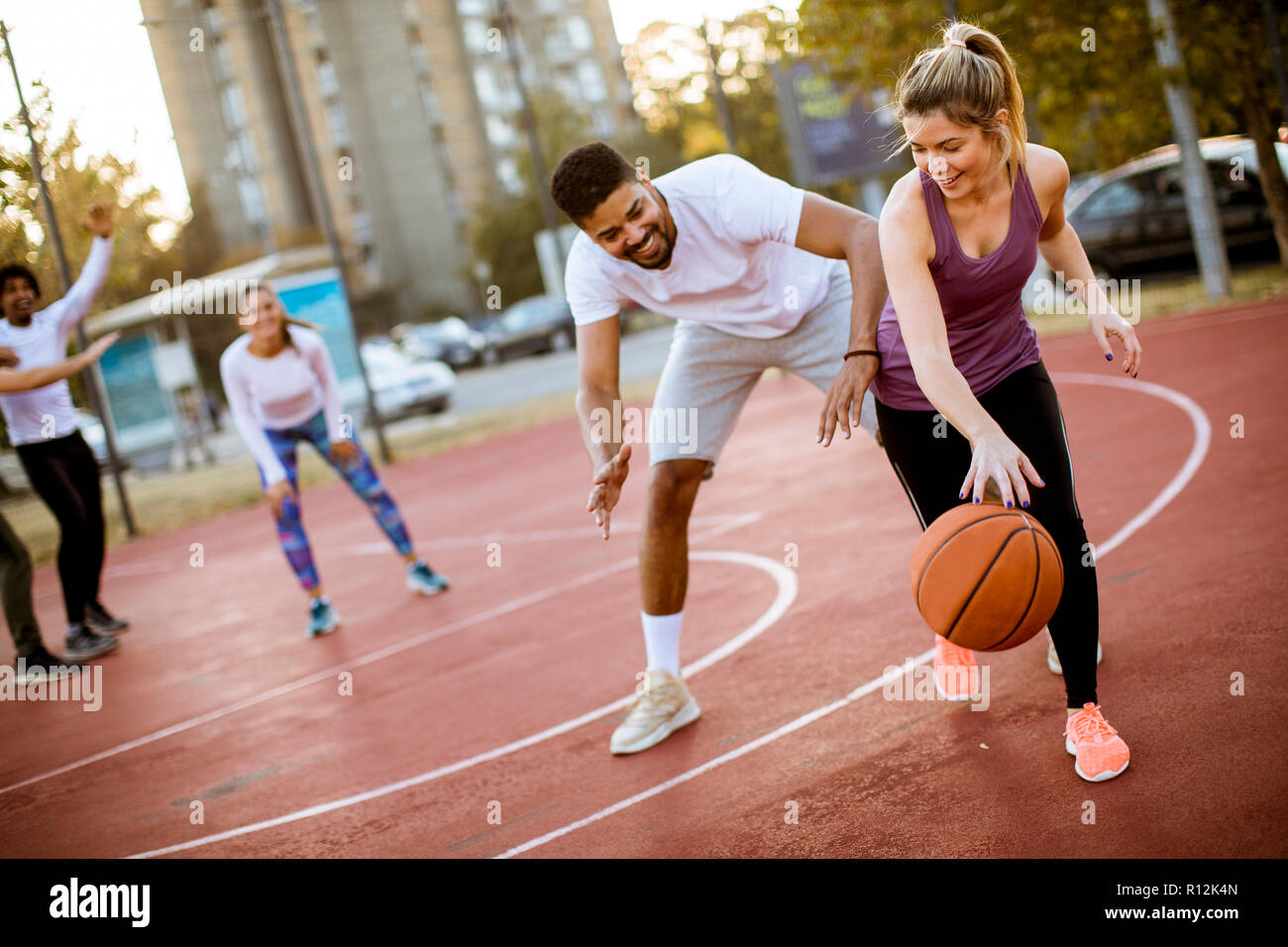 Group of multiethnic young people playing basketball on court Stock ...