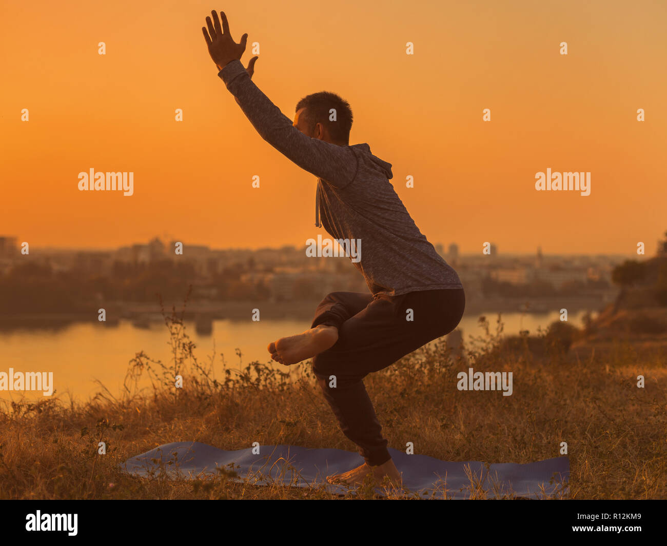 Man doing yoga on sunset with city view, variation of Chair Pose ...