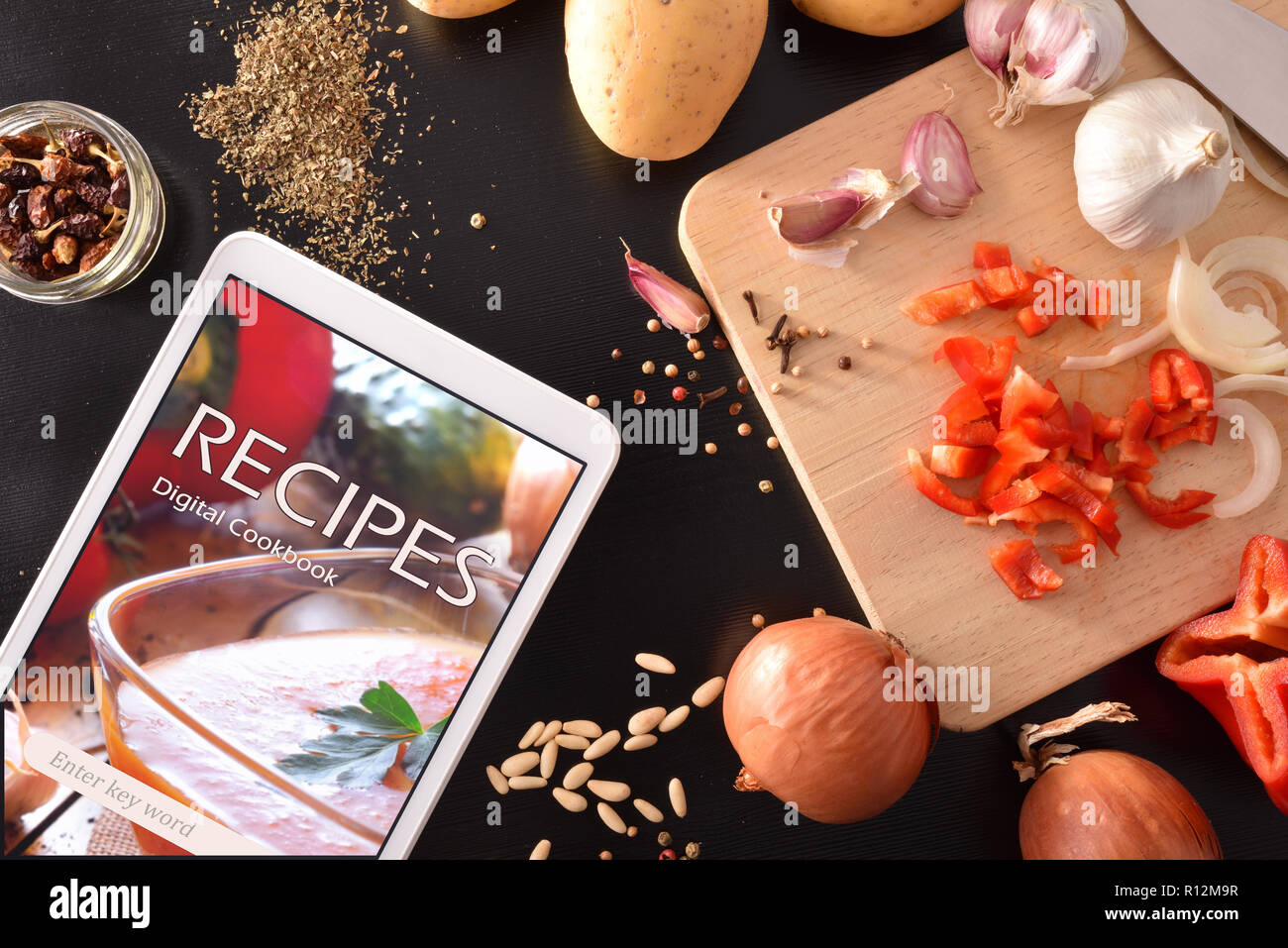 Tablet with online recipes app and ingredients background. Use of the ...
