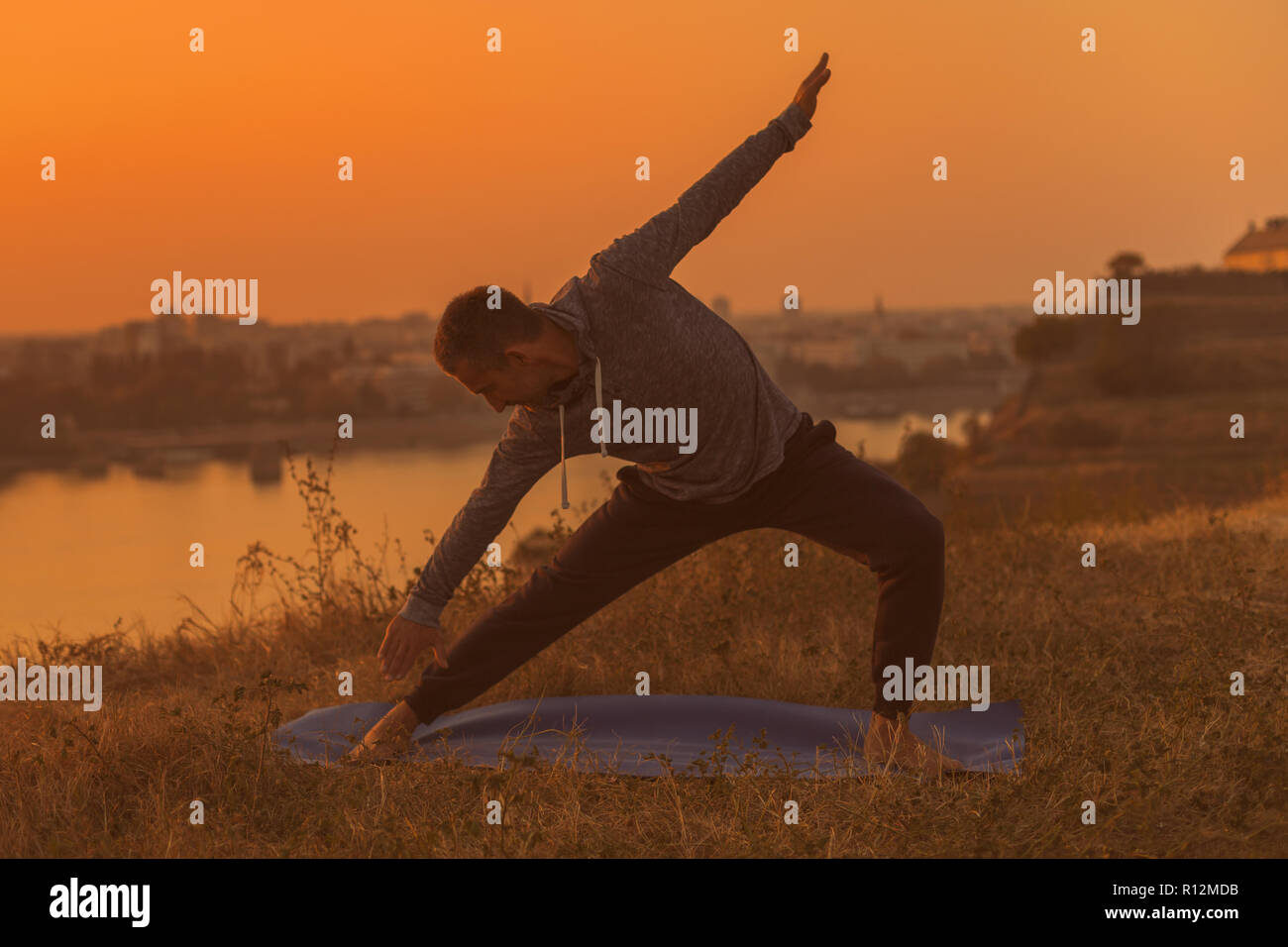Man doing yoga on sunset with city view Stock Photo - Alamy