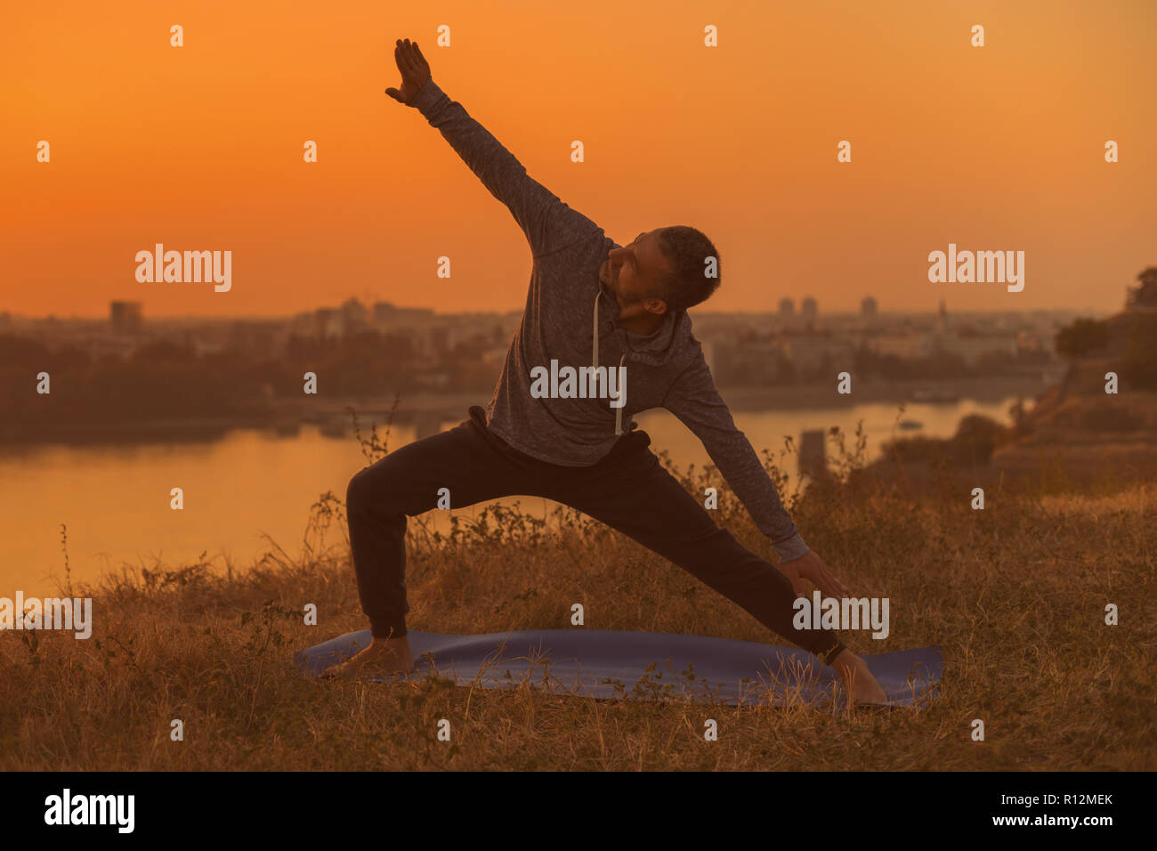 Man doing yoga on sunset with city view Stock Photo - Alamy
