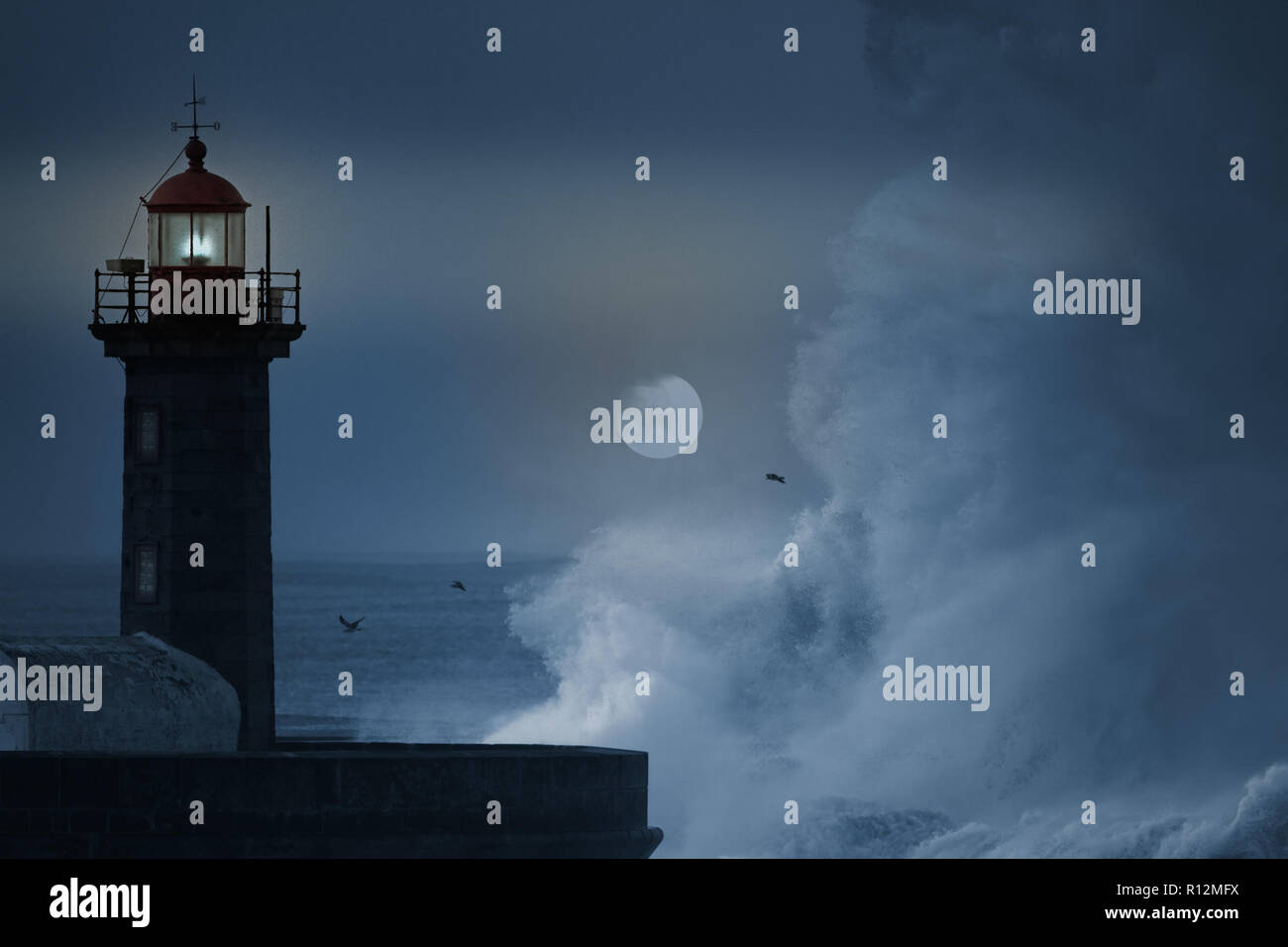 Big wave breaking over lighthouse in an overcast night of full moon ...