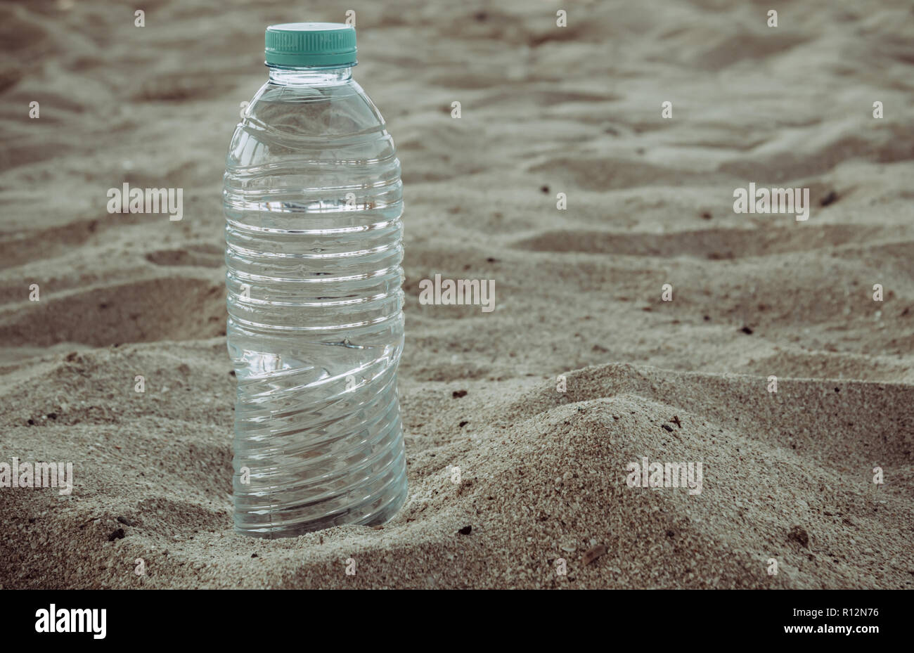 Cold drinking water in transparent bottles on sandy beach by the sea ...
