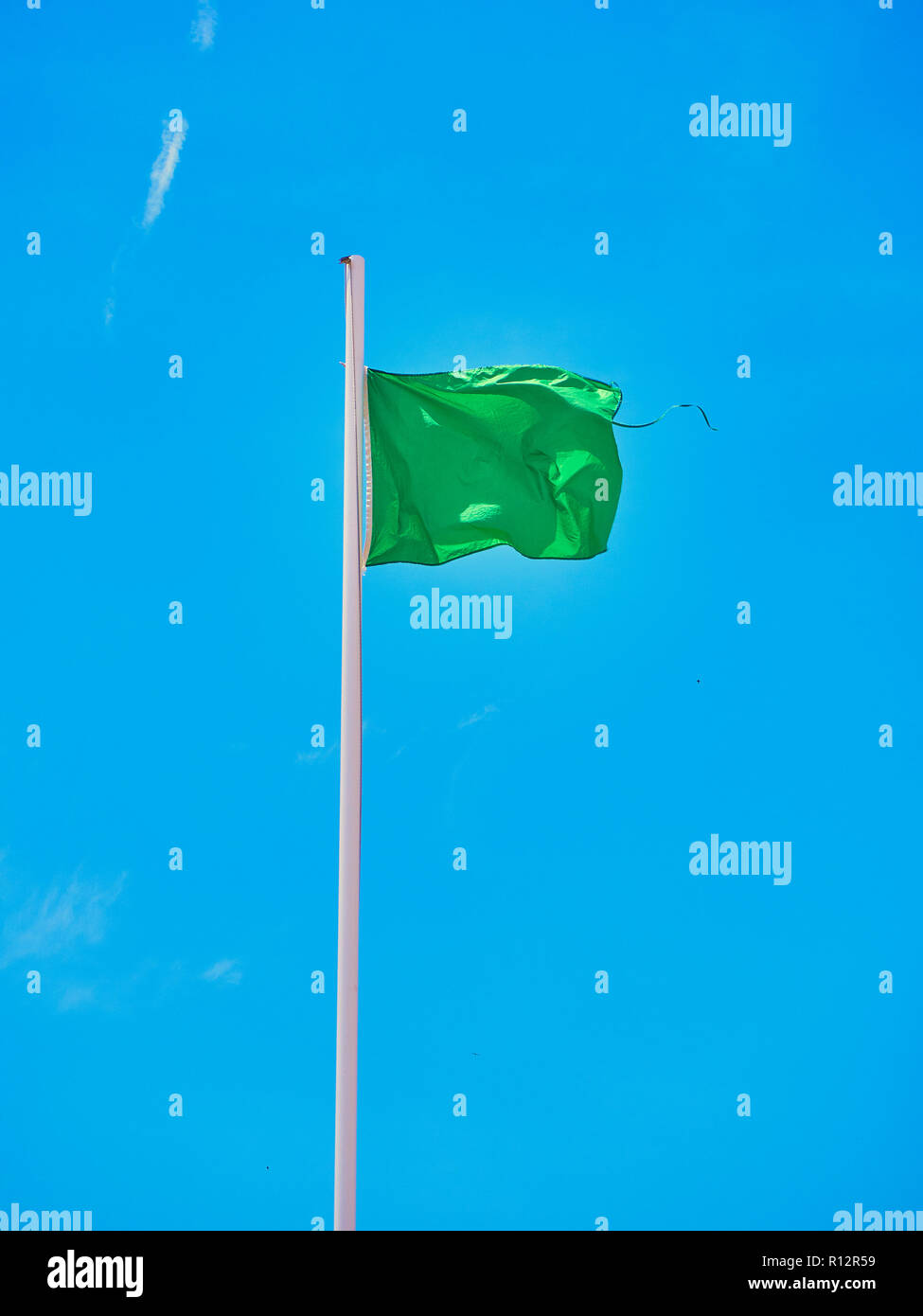 A green lifeguard flag on a beach over a blue sky Stock Photo - Alamy