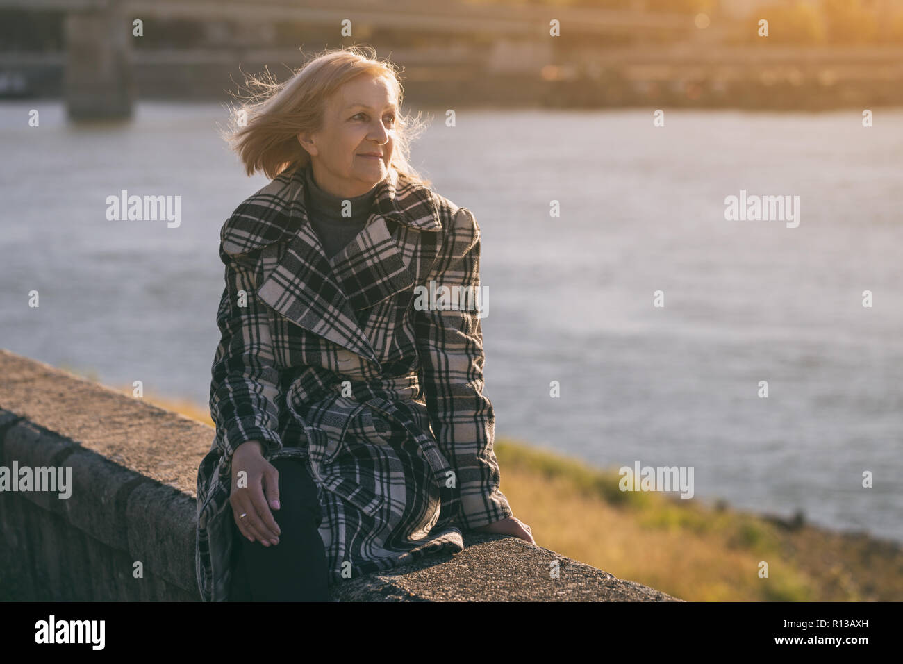 Senior woman enjoys sitting by the river Stock Photo - Alamy