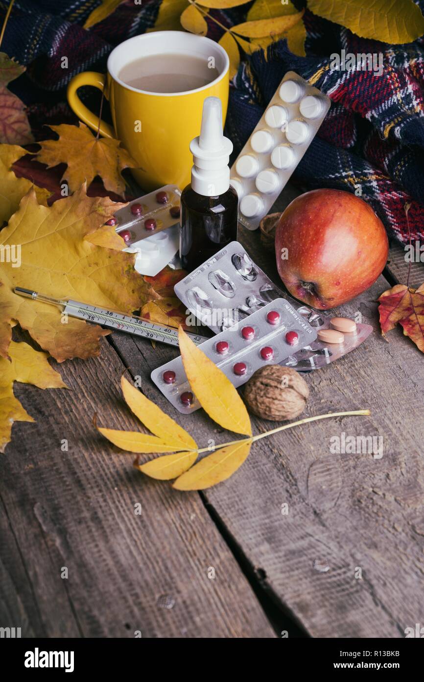 Fall and health care. cup of tea, pills and thermometer on a wooden ...