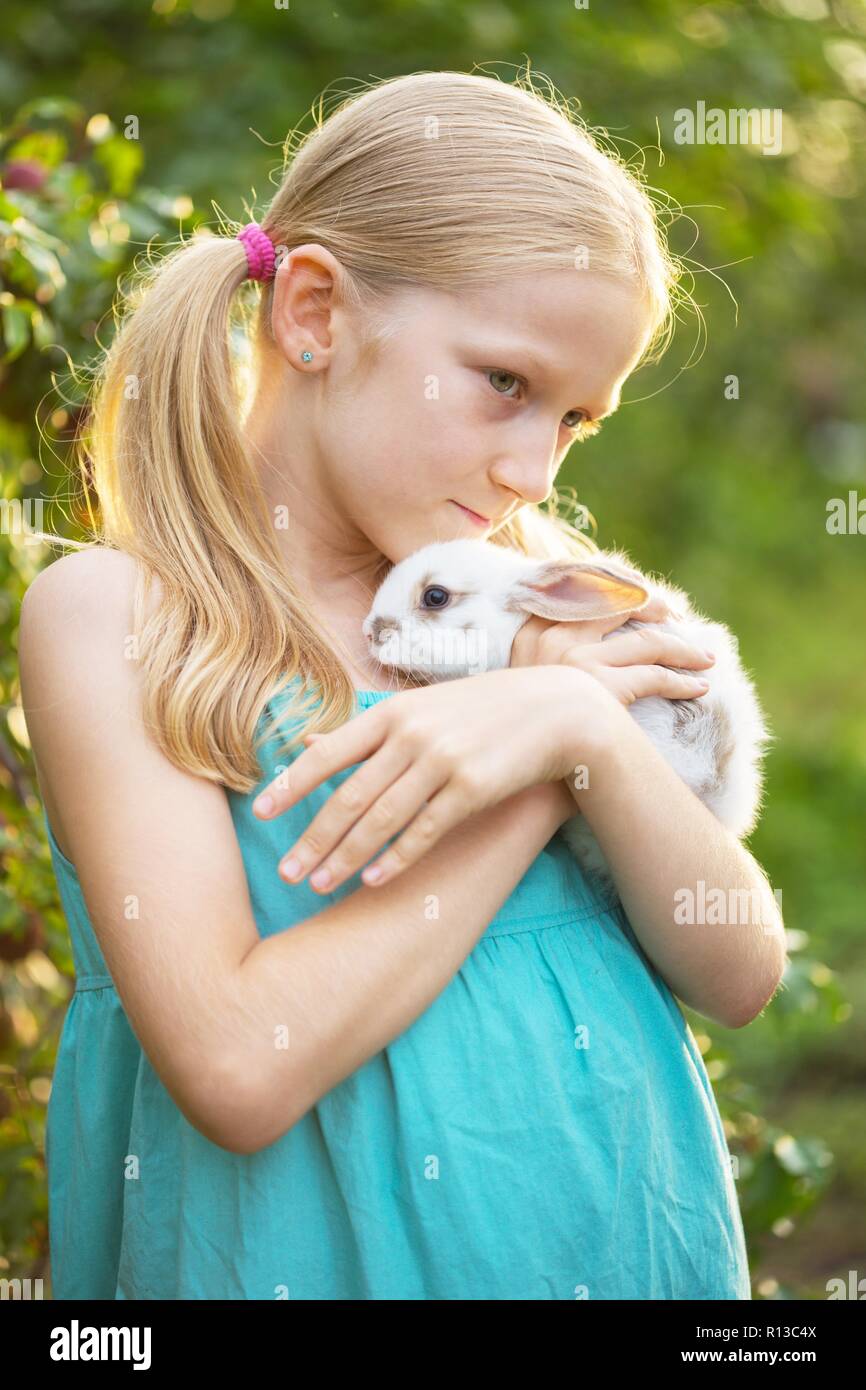 beautiful little girl holding in hands white rabbit at the garden Stock ...