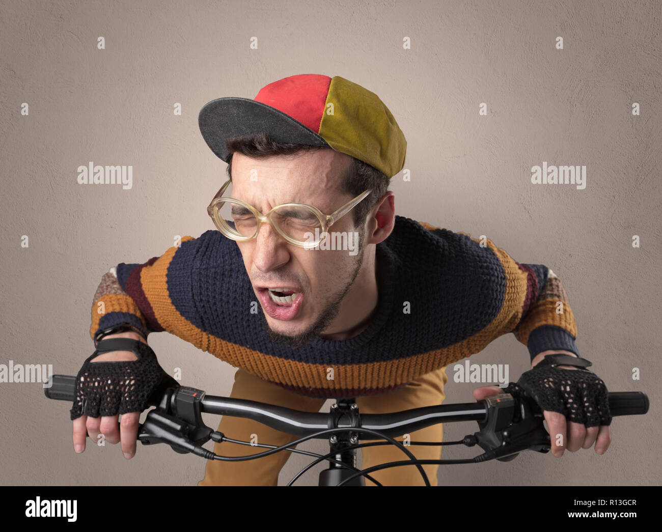 Nerd young foolish biker on a bike with oldschool outfit Stock Photo - Alamy
