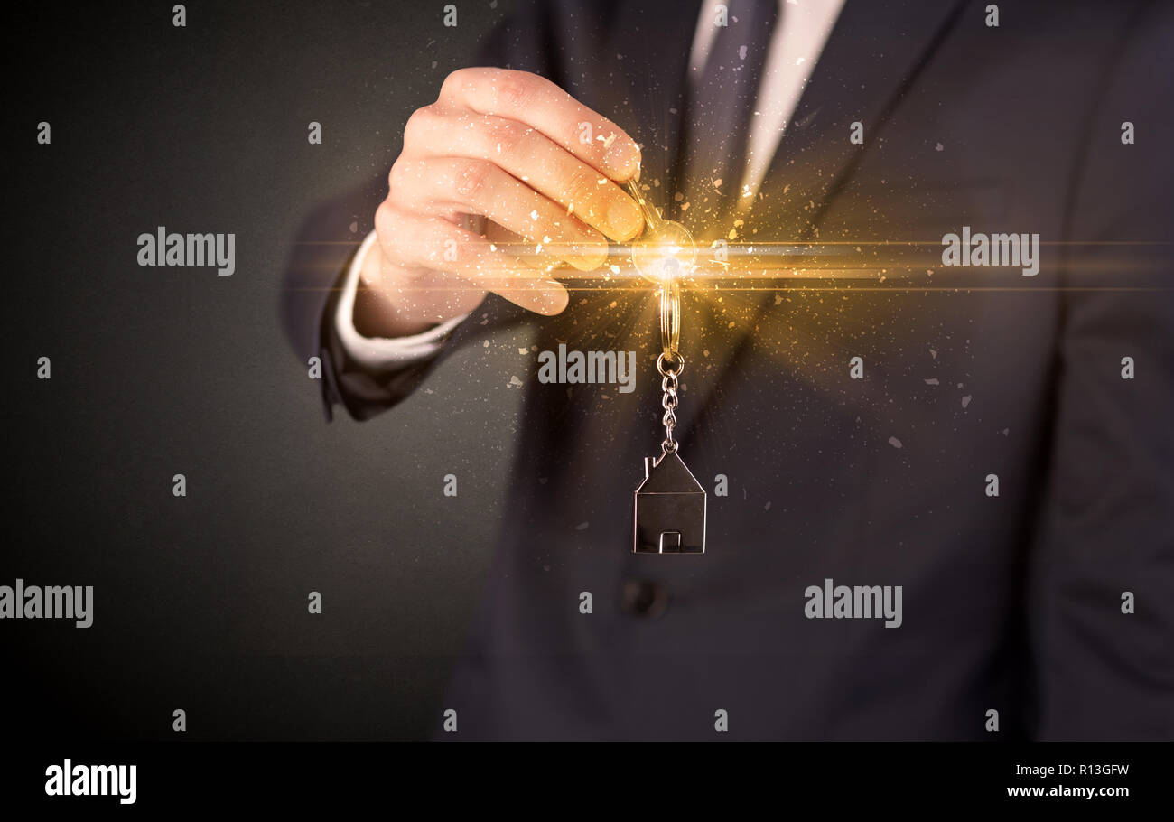 Businessman hand over shiny keys in dark suit with dark background ...