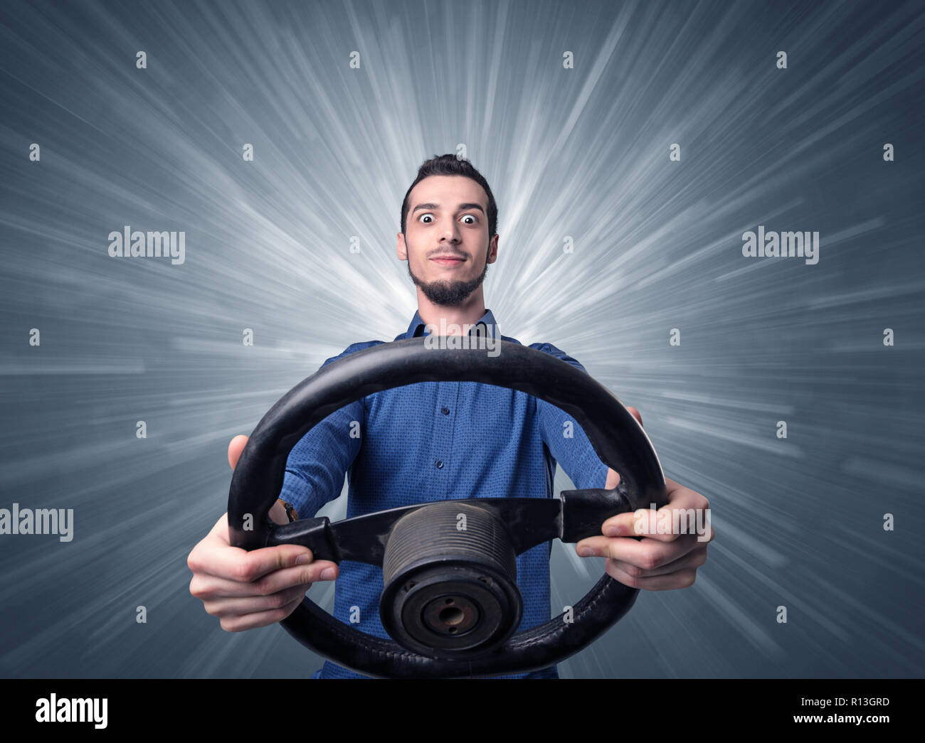 Young man holding black steering wheel with white lines behind him ...