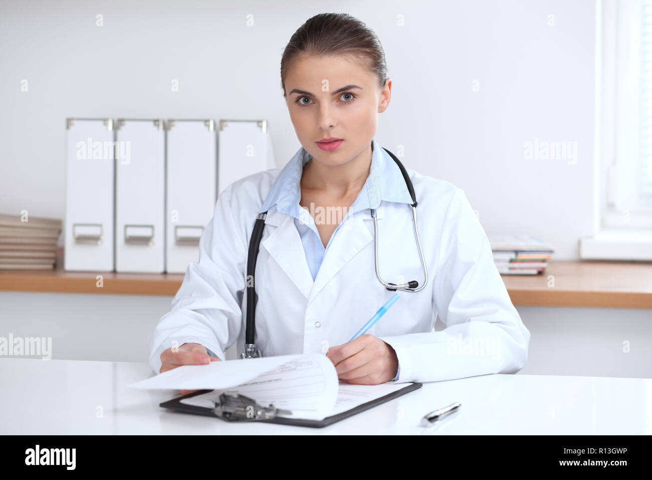 Doctor woman writing papers at the desk in hospital office. Medicine ...