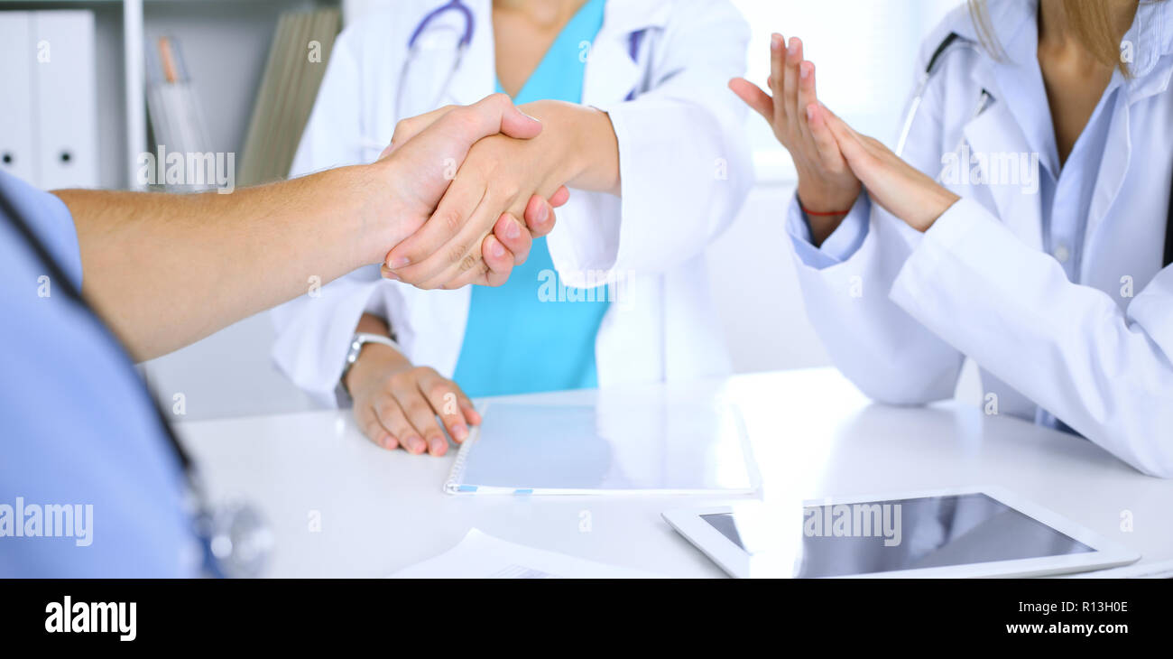 Two doctors shaking hands to each other at meeting. Teamwork and ...