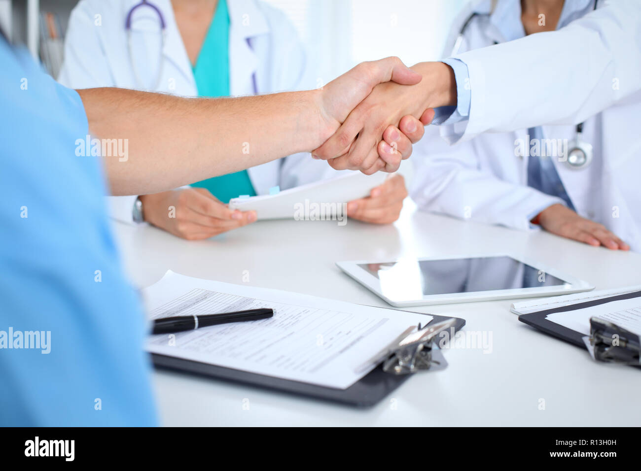 Two doctors shaking hands to each other at meeting. Teamwork and ...