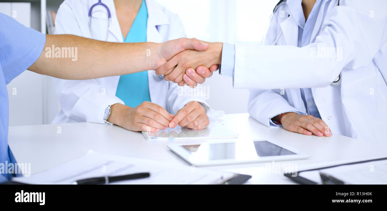 Two doctors shaking hands to each other at meeting. Teamwork and ...