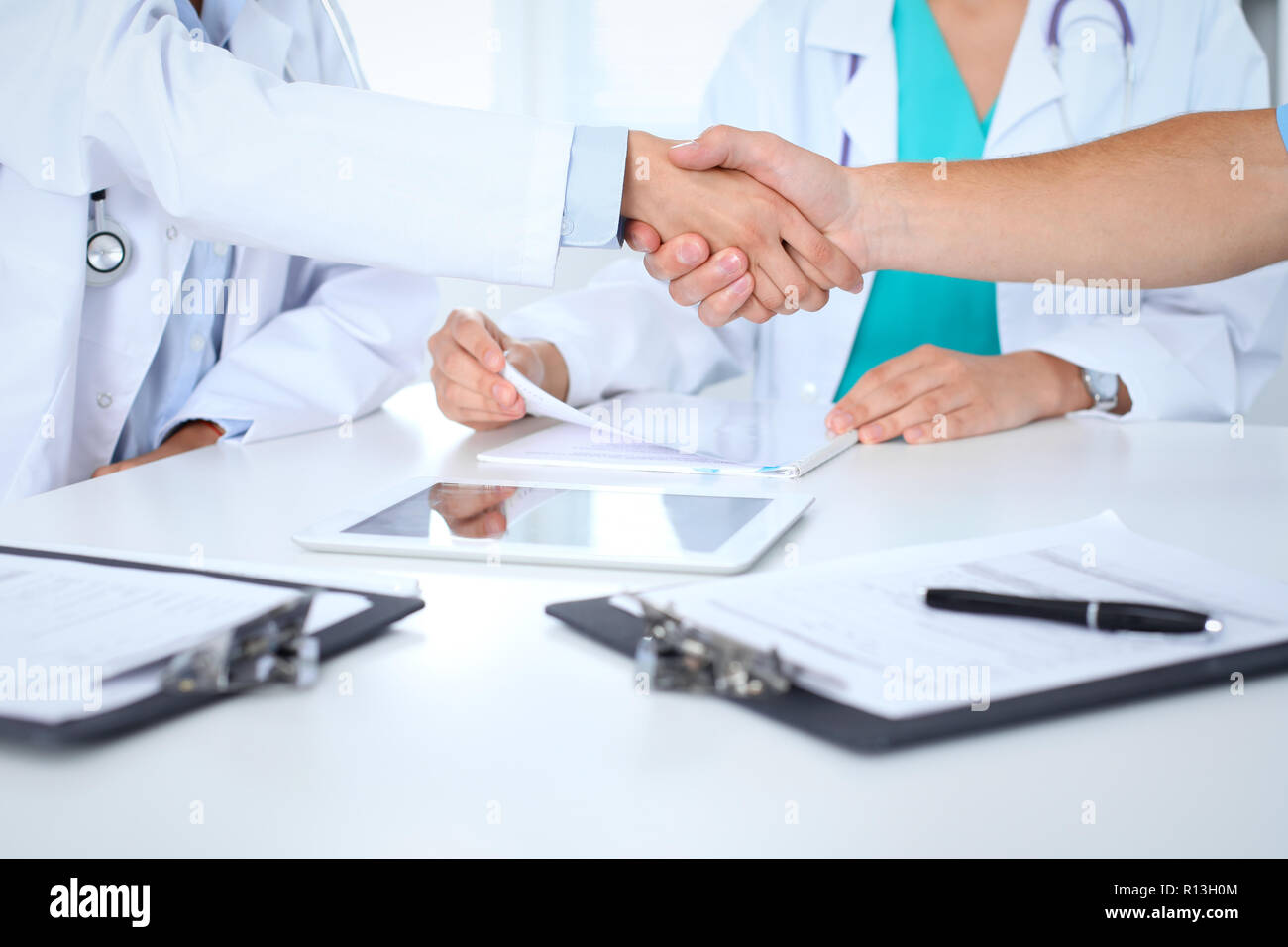 Two doctors shaking hands to each other at meeting. Teamwork and ...