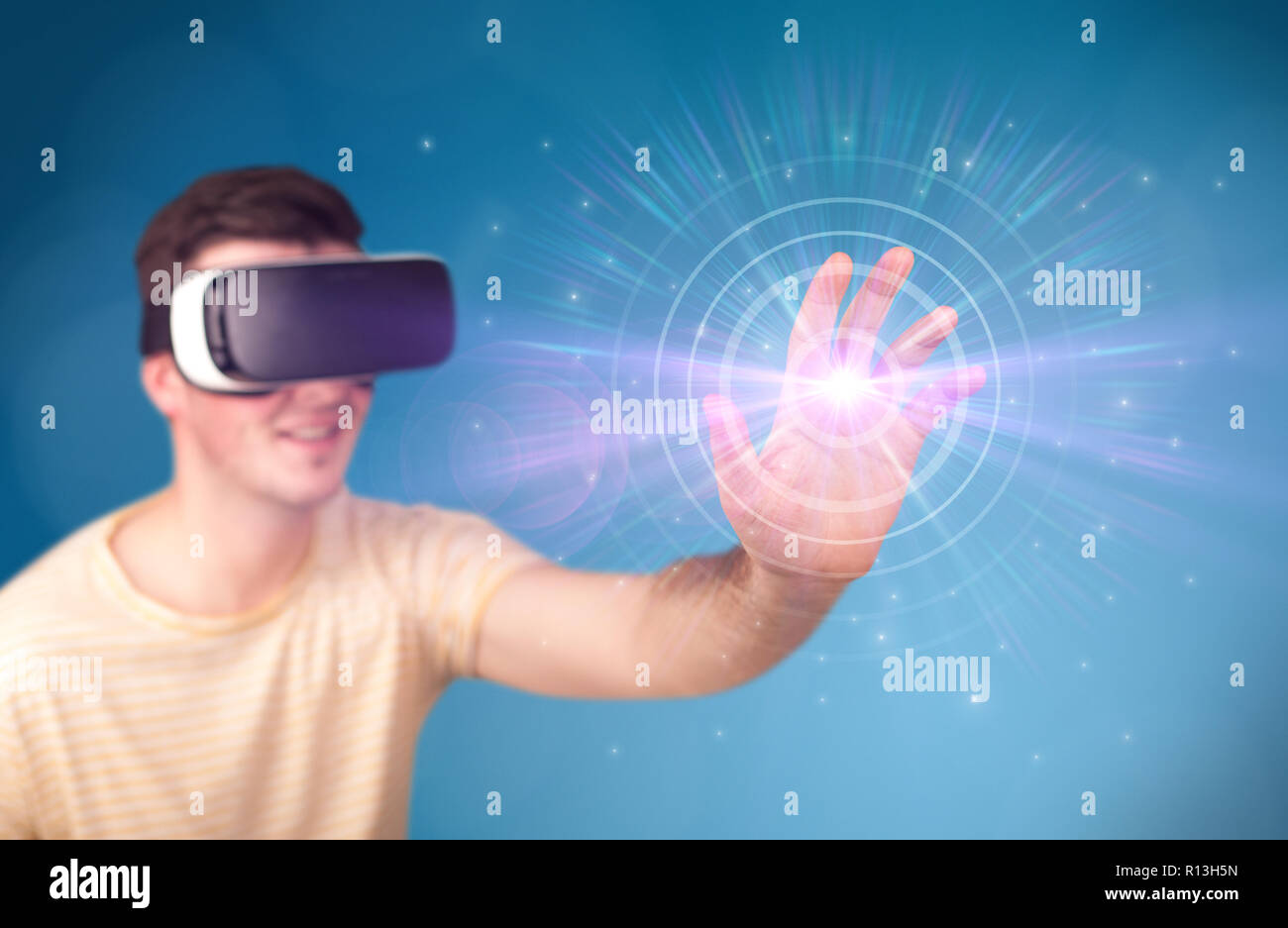 Young impressed man wearing virtual reality goggles with blue circles ...