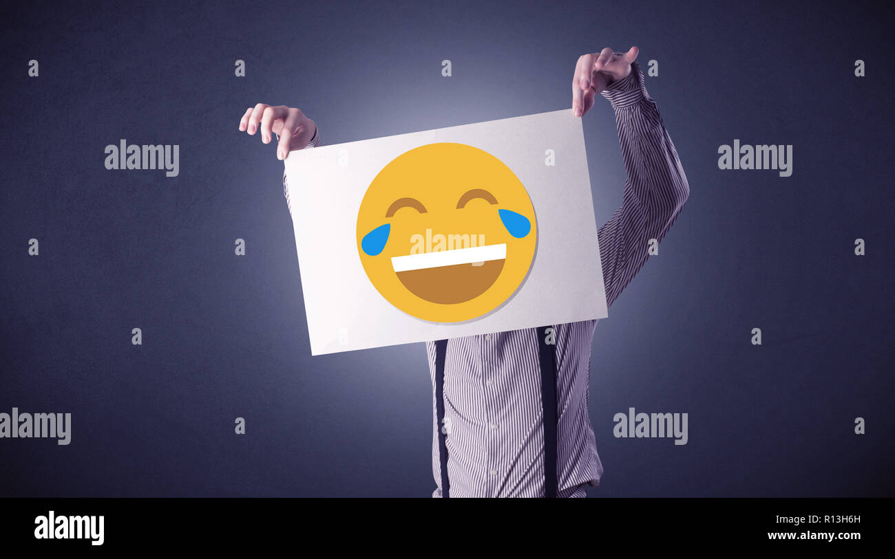Young businessman hiding behind a laughing emoticon on cardboard Stock ...