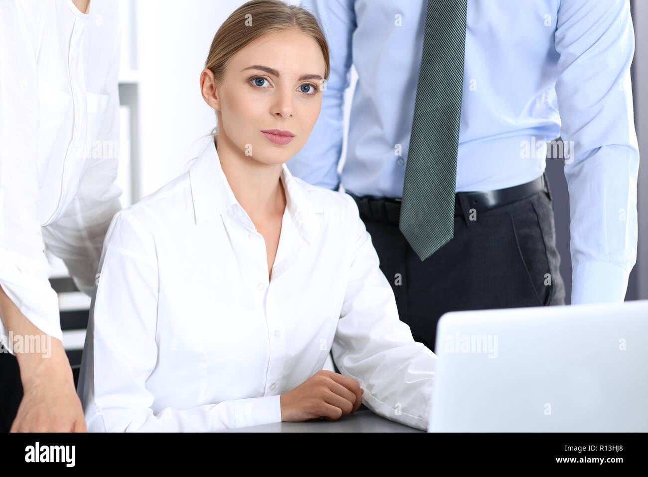 Group of business people using laptop computer while standing in office ...