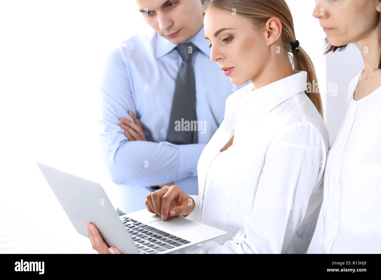 Group of business people using laptop computer while standing in office ...