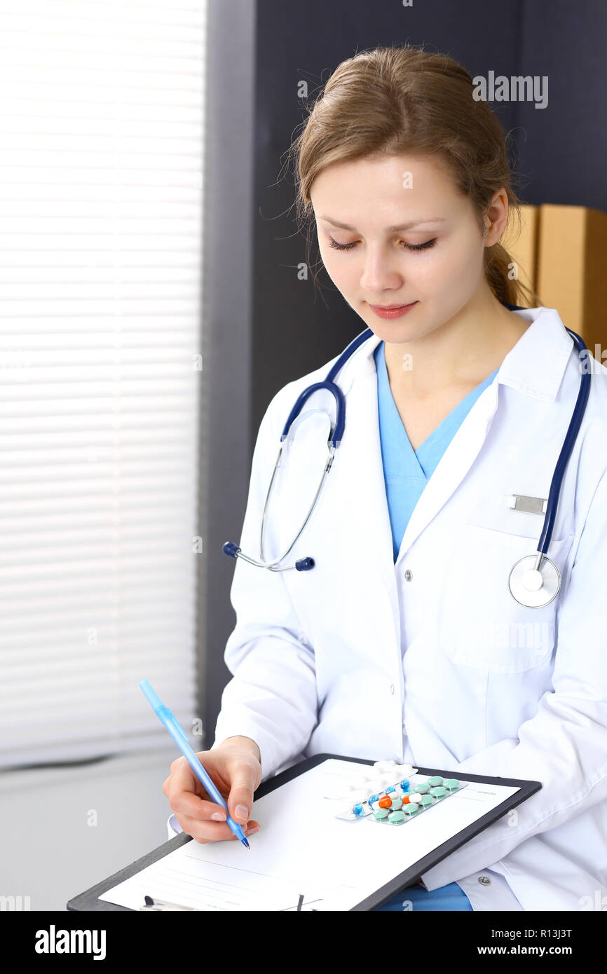 Woman doctor at work at hospital. Young female physician write ...