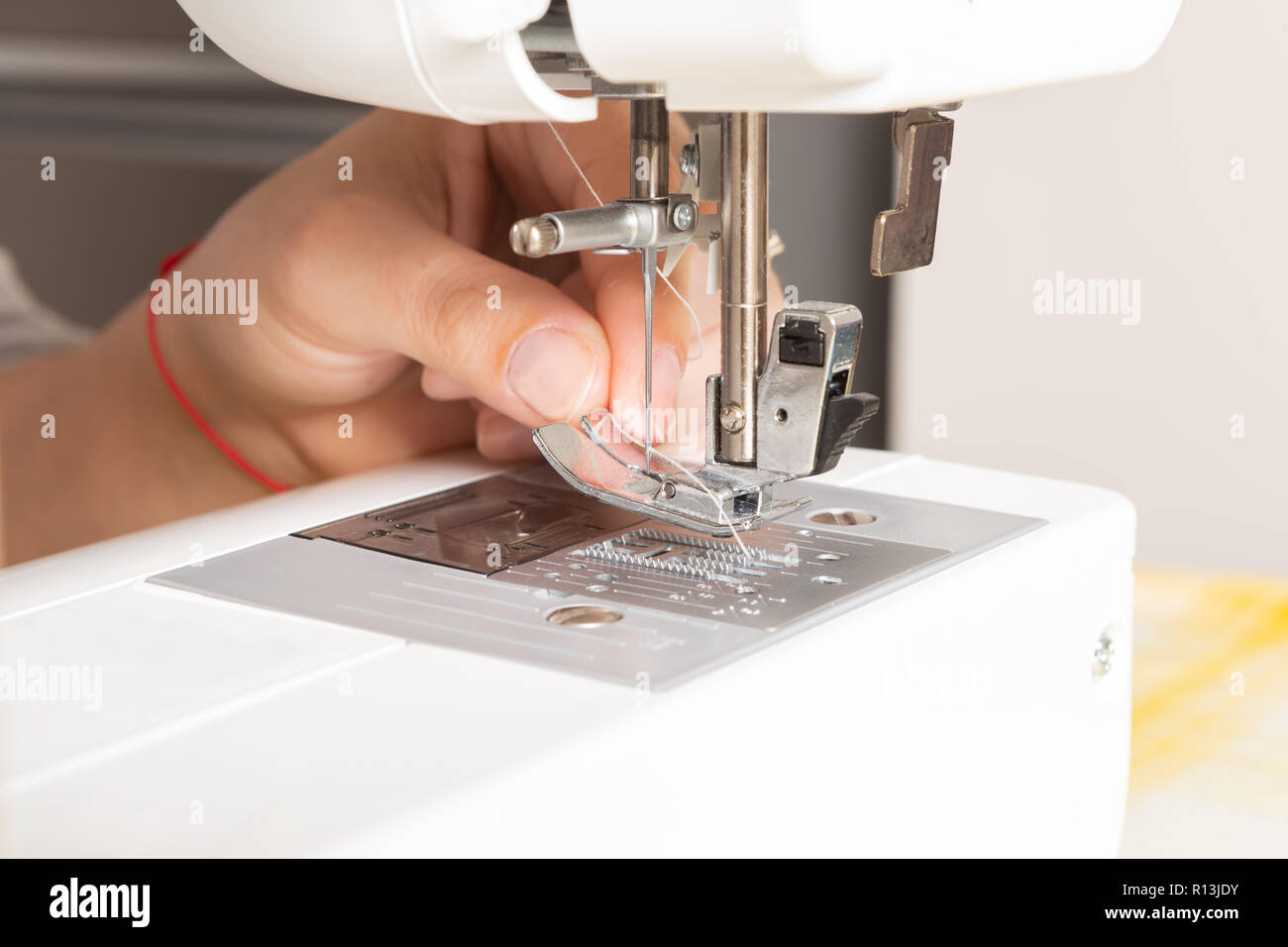 Sewing machine being prepared by someone for tailoring by putting ...