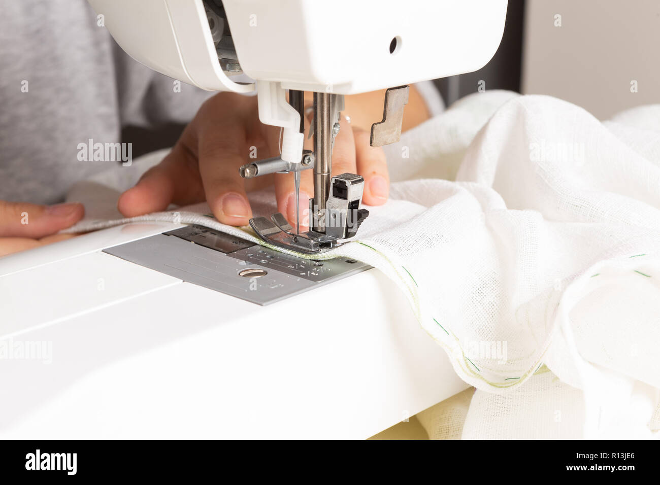 Person using sewing machine for stitching white fabric Stock Photo - Alamy