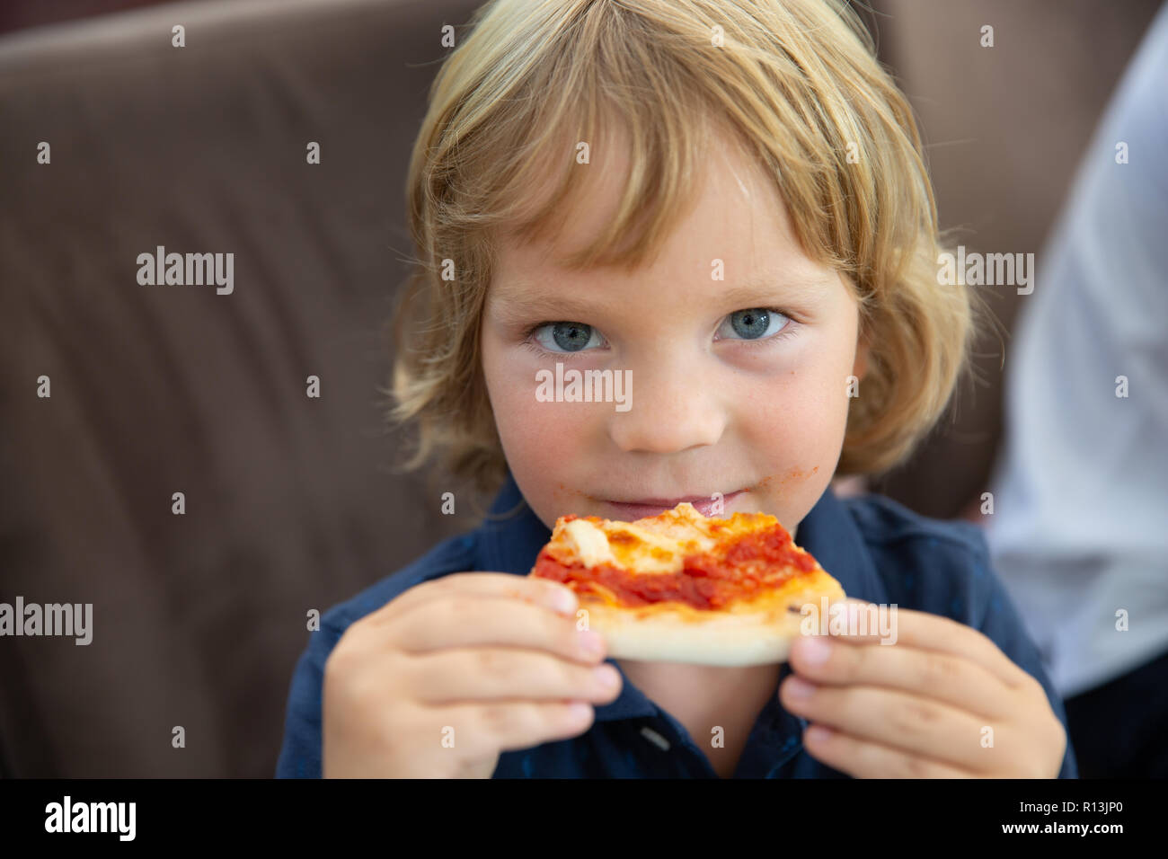 The cute boy is eating pizza in an Italian restaurant Stock Photo - Alamy