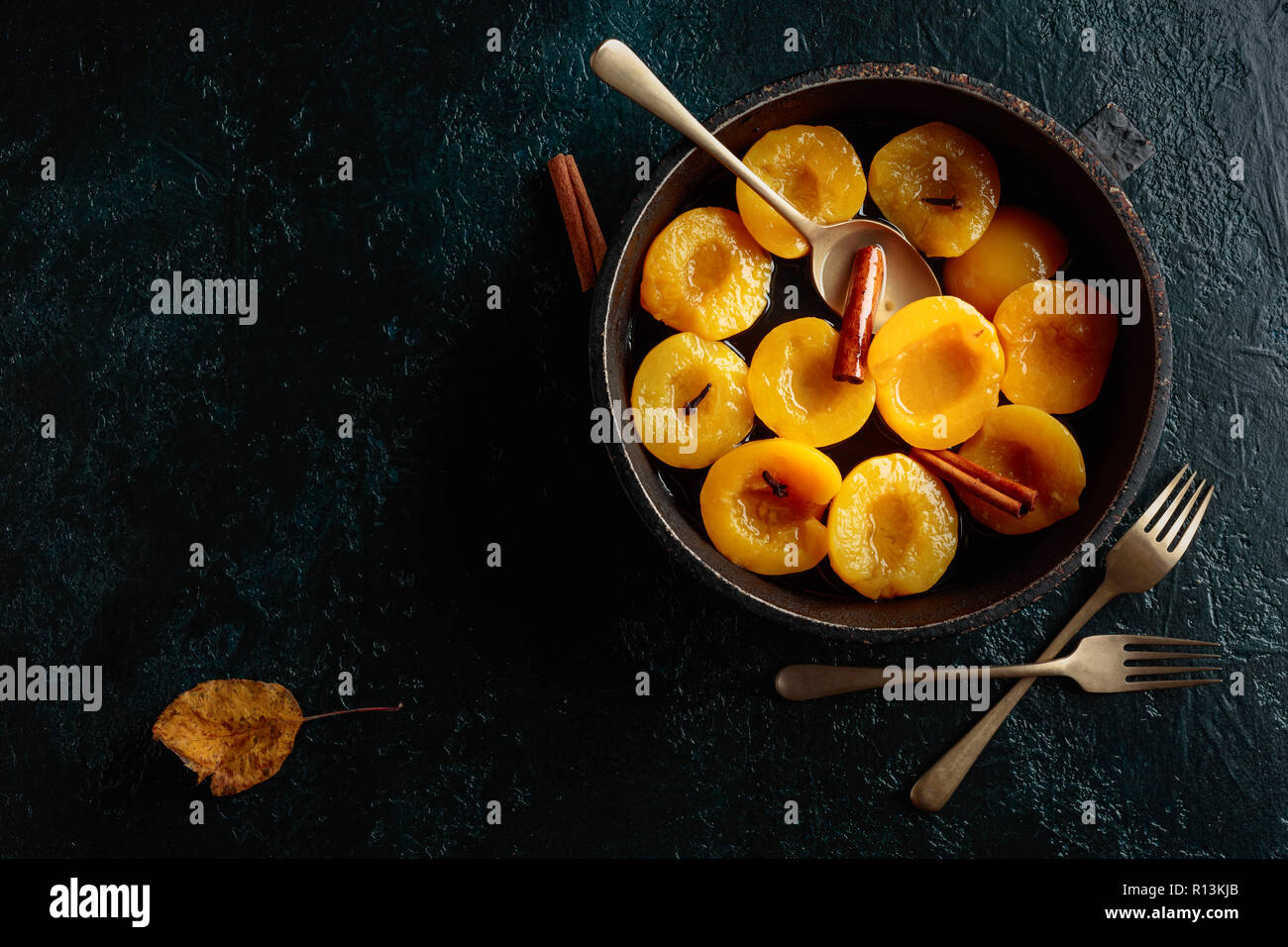 Peach dessert with cinnamon and cloves on a dark background, top view ...