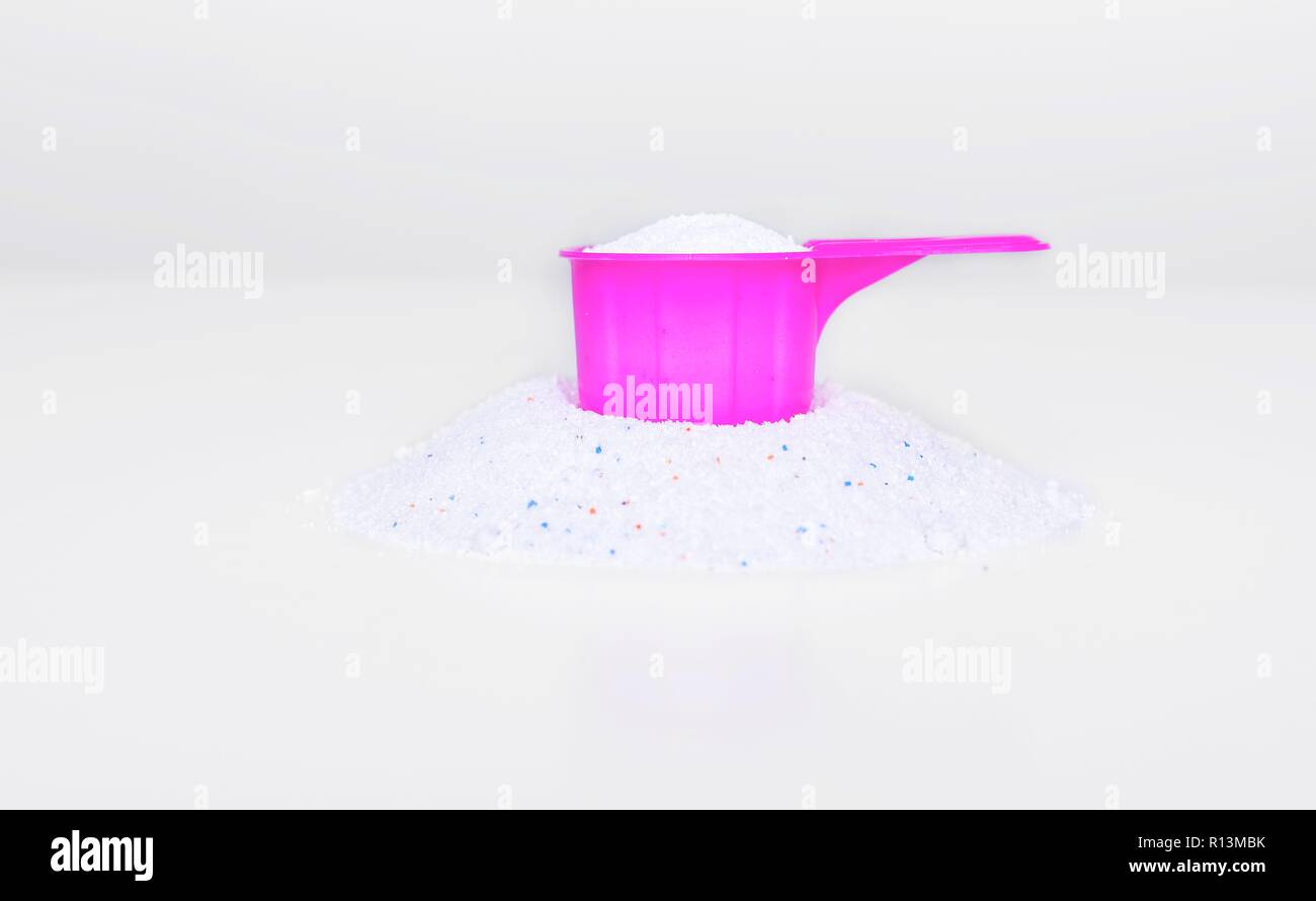 Washing powder in a measuring cup on a white table Stock Photo - Alamy