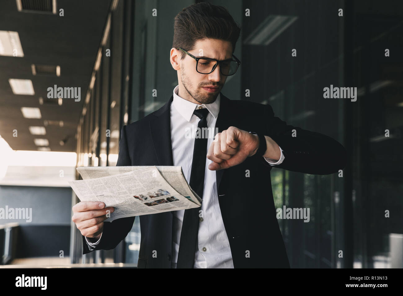 Image of handsome business man holding newspaper looking at watch clock ...