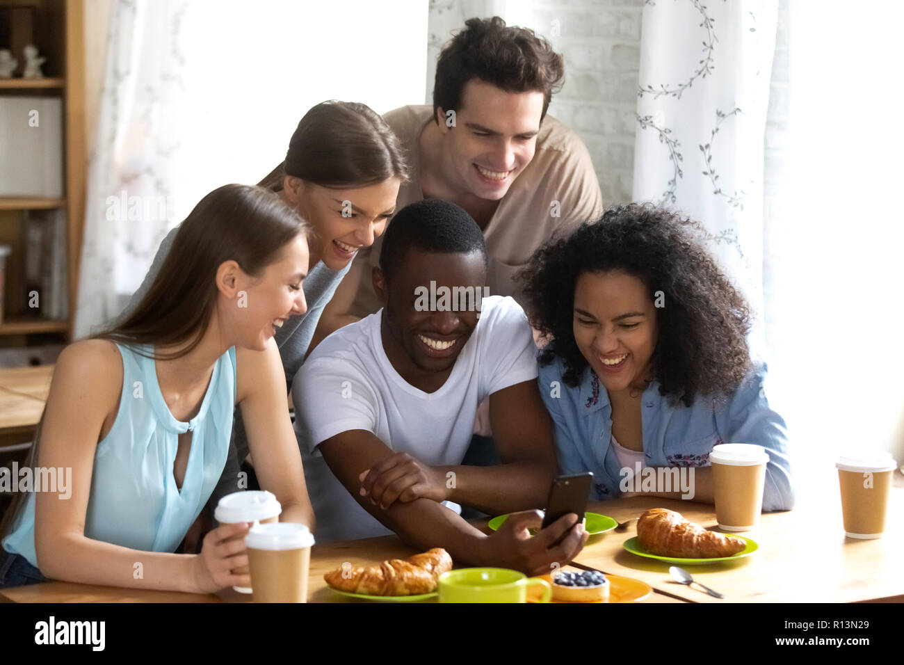 Cheerful Diverse Multiracial Millennial People Sitting At Table Indoors