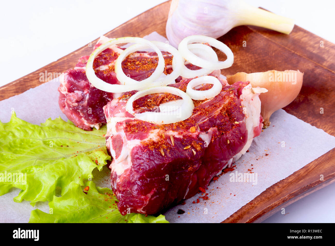 Raw beef edges, lettuce leaf, garlic, pepper grinder and spices on ...