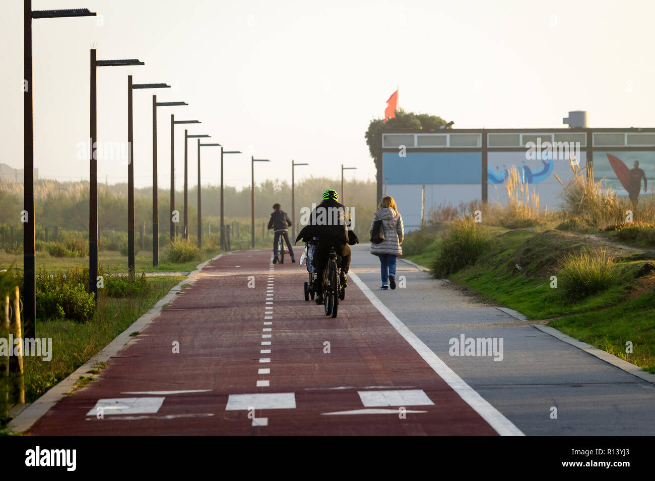 People walk along red cycle path. Bicycle. Man, Woman, Boy. Lamp Posts ...